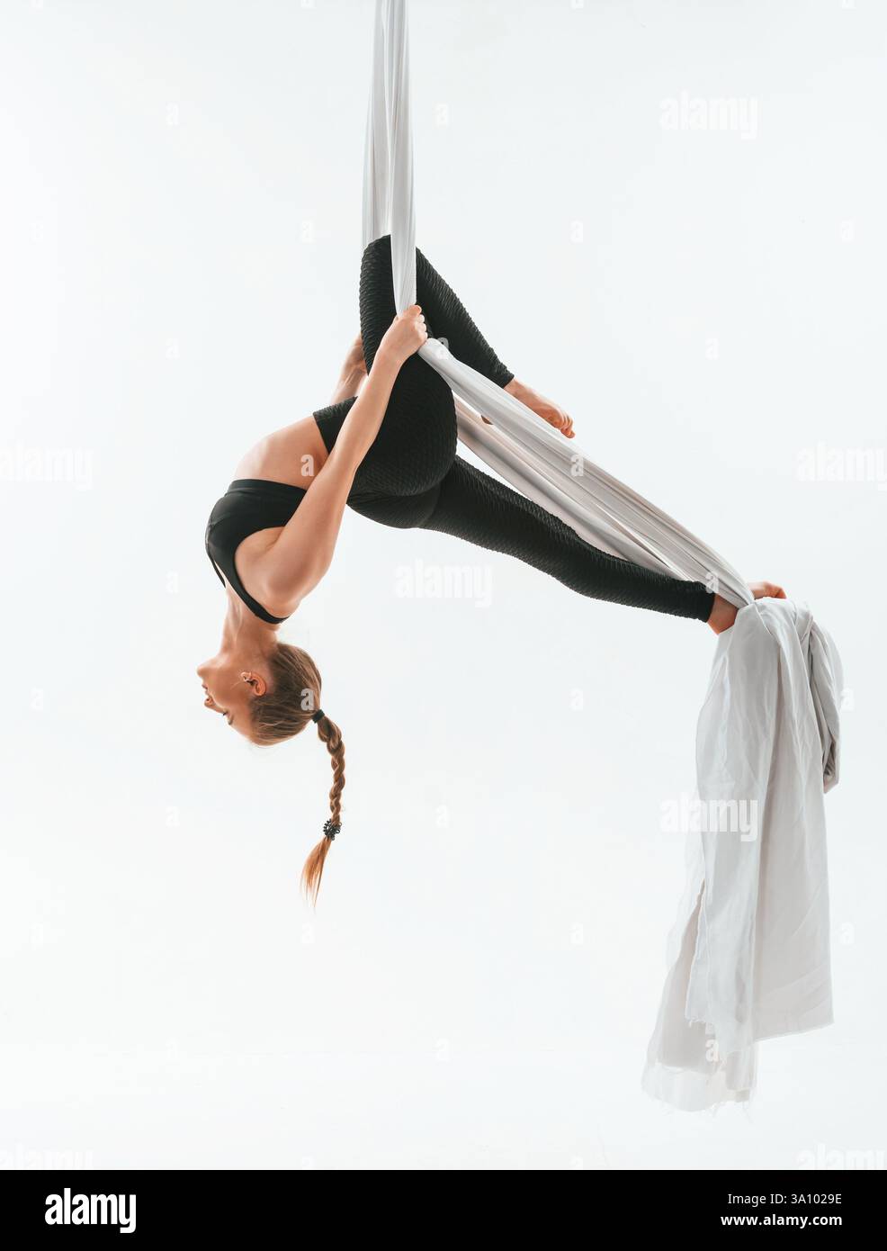 View from the side, hanging upside down. Young beautiful woman doing ...