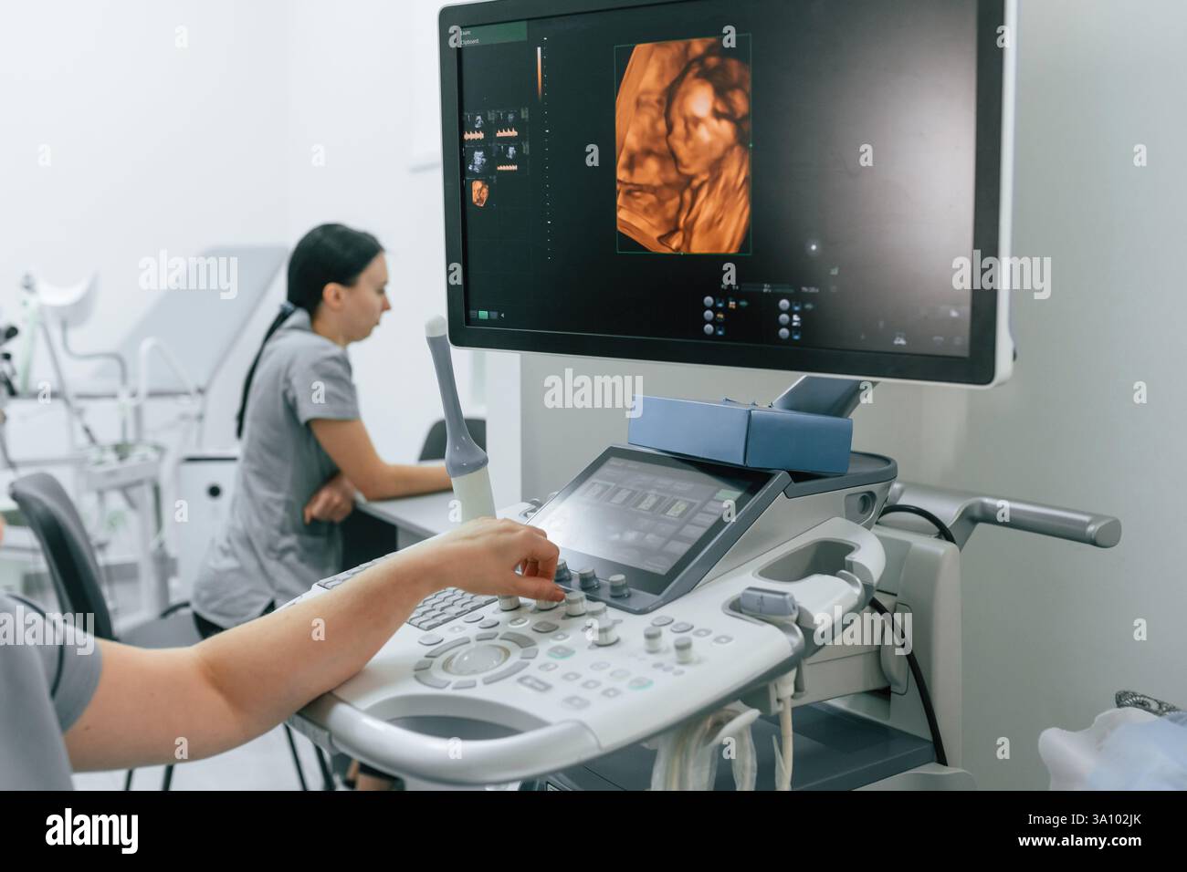 Nurse is working in the clinic, doing an ultrasound scan of the belly ...