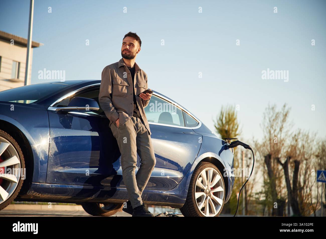Standing and waiting for his automobile to charge. Man is near his ...