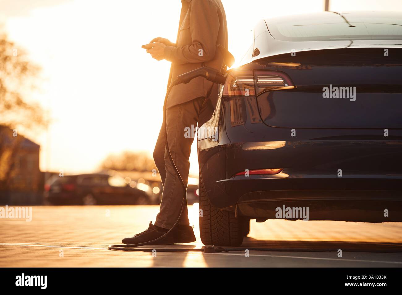 Bright sunlight. Man is standing near his electric car outdoors Stock ...