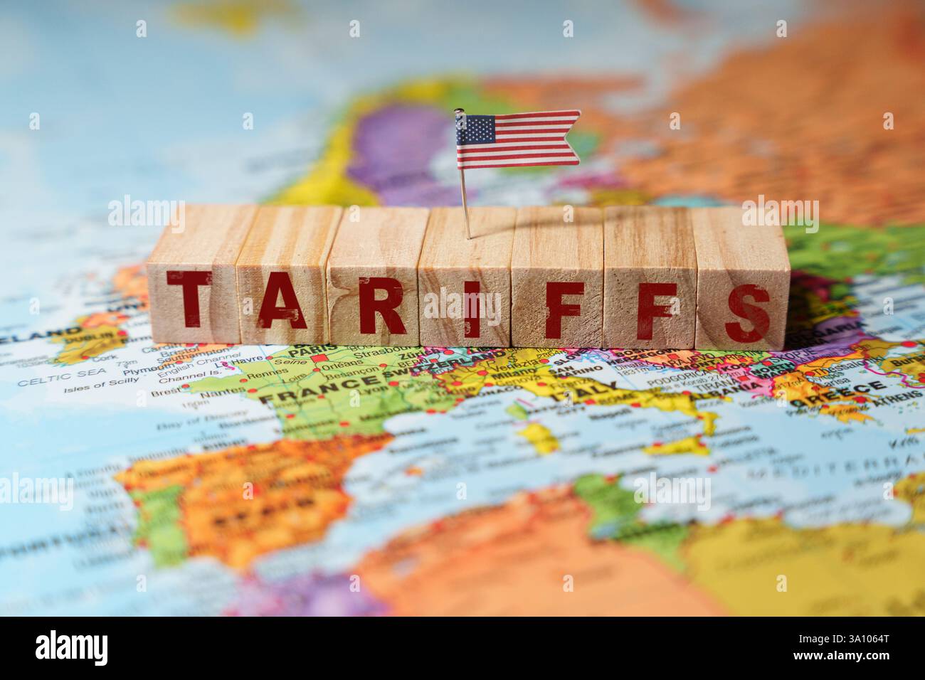 Wooden blocks spelling TARIFFS with a U.S. flag on top, placed on an ...