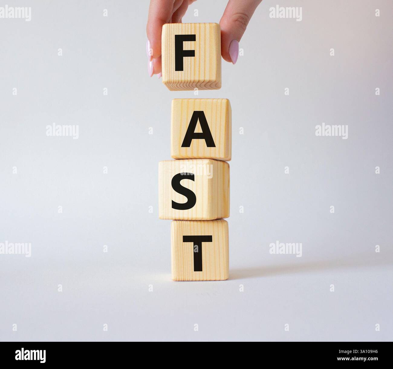 Fast symbol. Concept word Fast on wooden cubes. Businessman hand. Beautiful white background ...