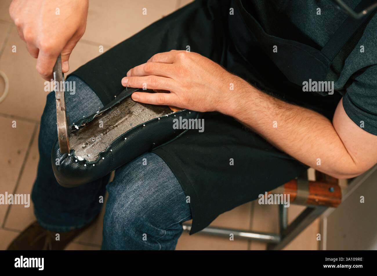 Working with nails on the shoe. Close up view of man that is sitting ...