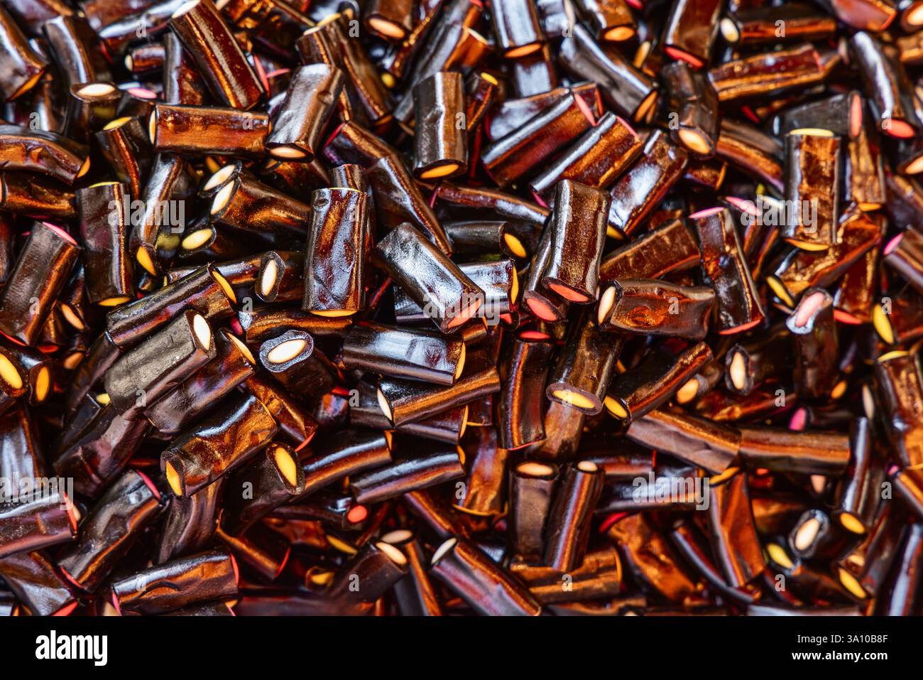 Background of licorice tube shaped candies with a glossy black surface ...
