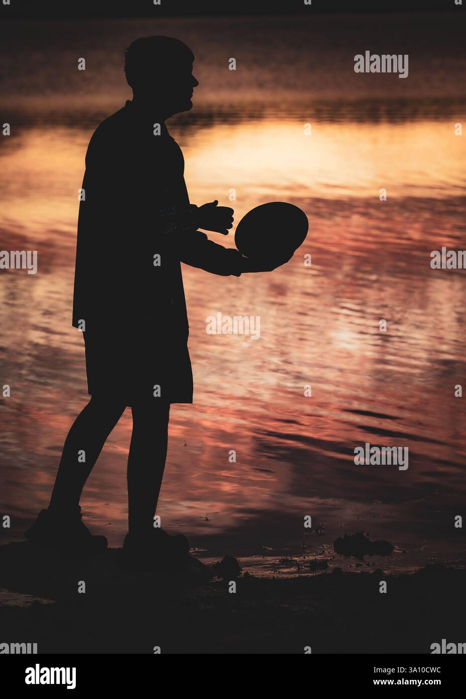Silhouette of boy playing with a ball by water at Leslie Dam in Warwick ...