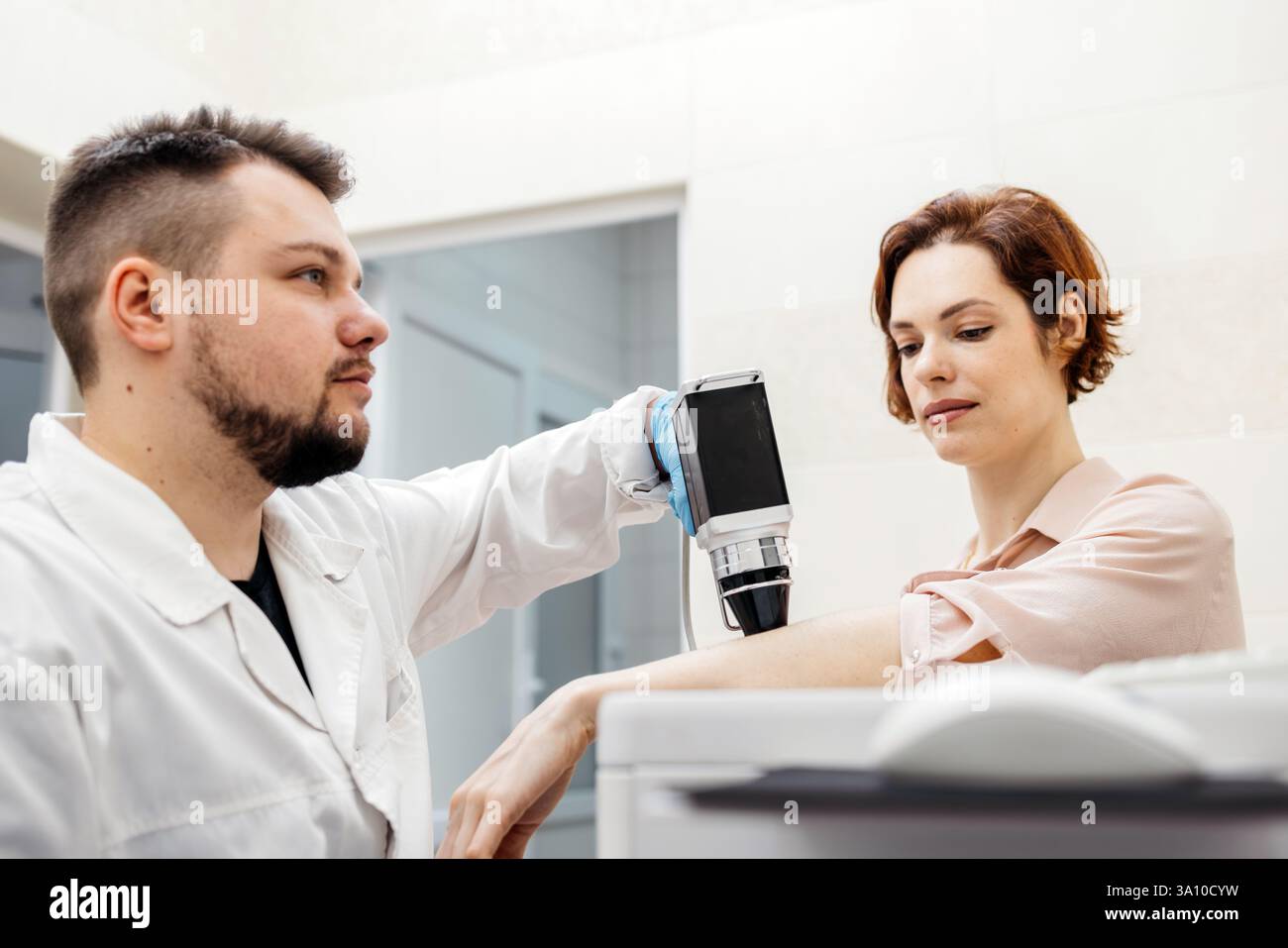 A dermatologist examines and analyzes the skin of a young patient in a ...