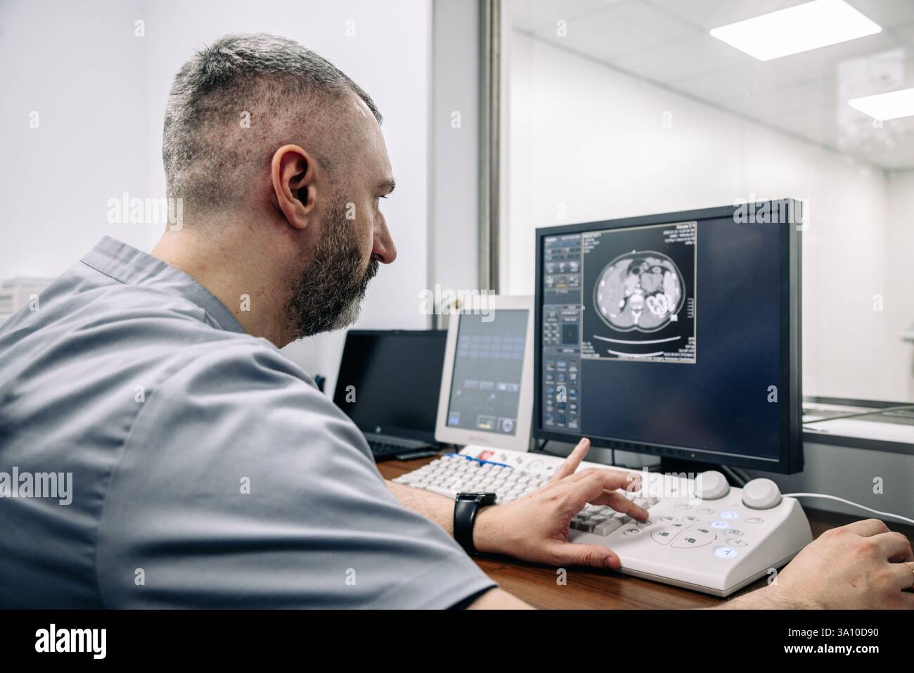 A doctor reviews X-ray images in the MRI control room while monitoring ...