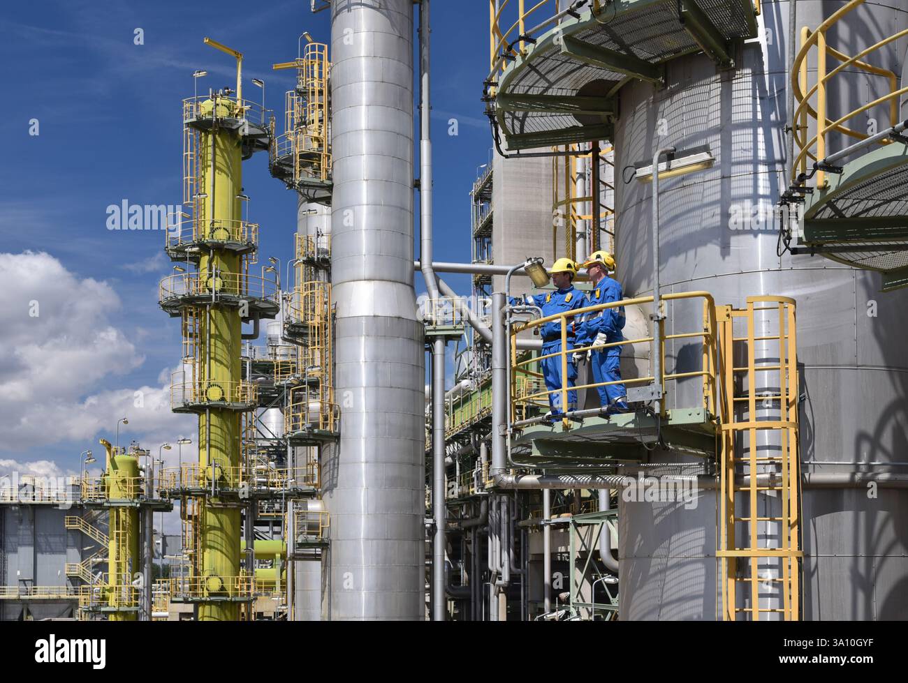 Workers in work clothes in a rafinery - modern equipment and buildings ...