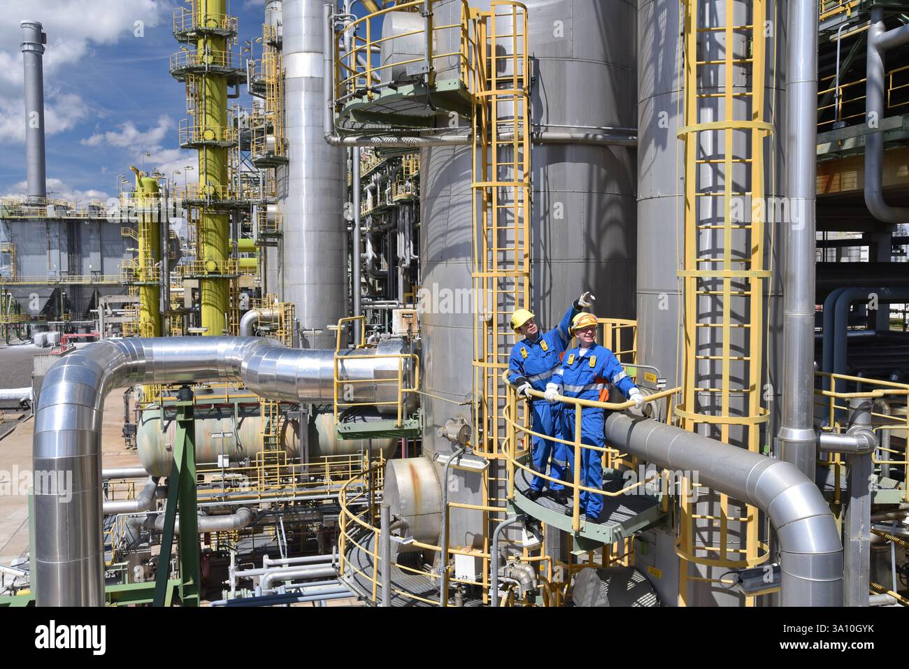 Workers in work clothes in a rafinery - modern equipment and buildings ...