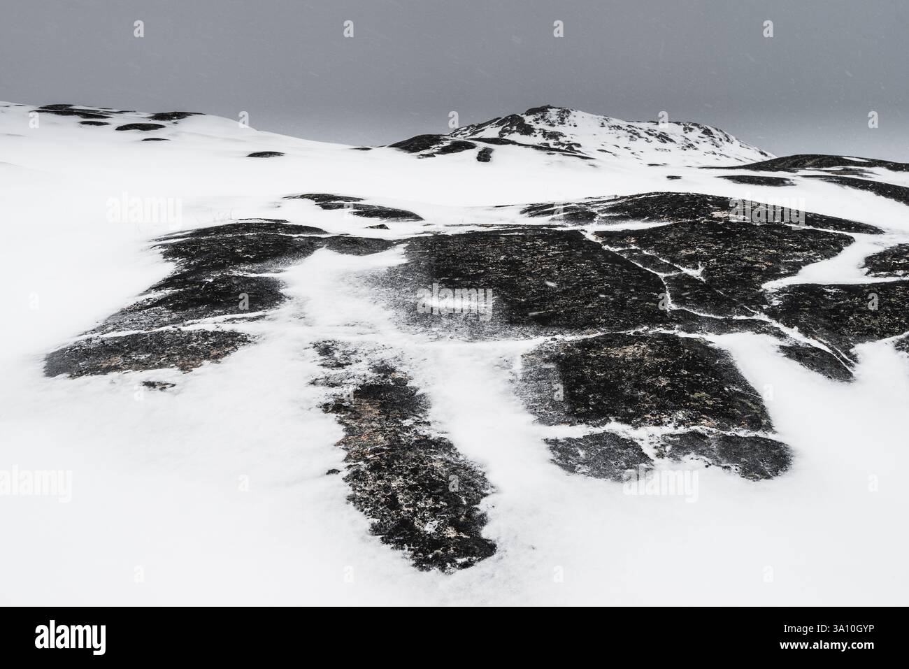 Expansive snow blankets the rocky terrain of Greenland, with a subtle ...
