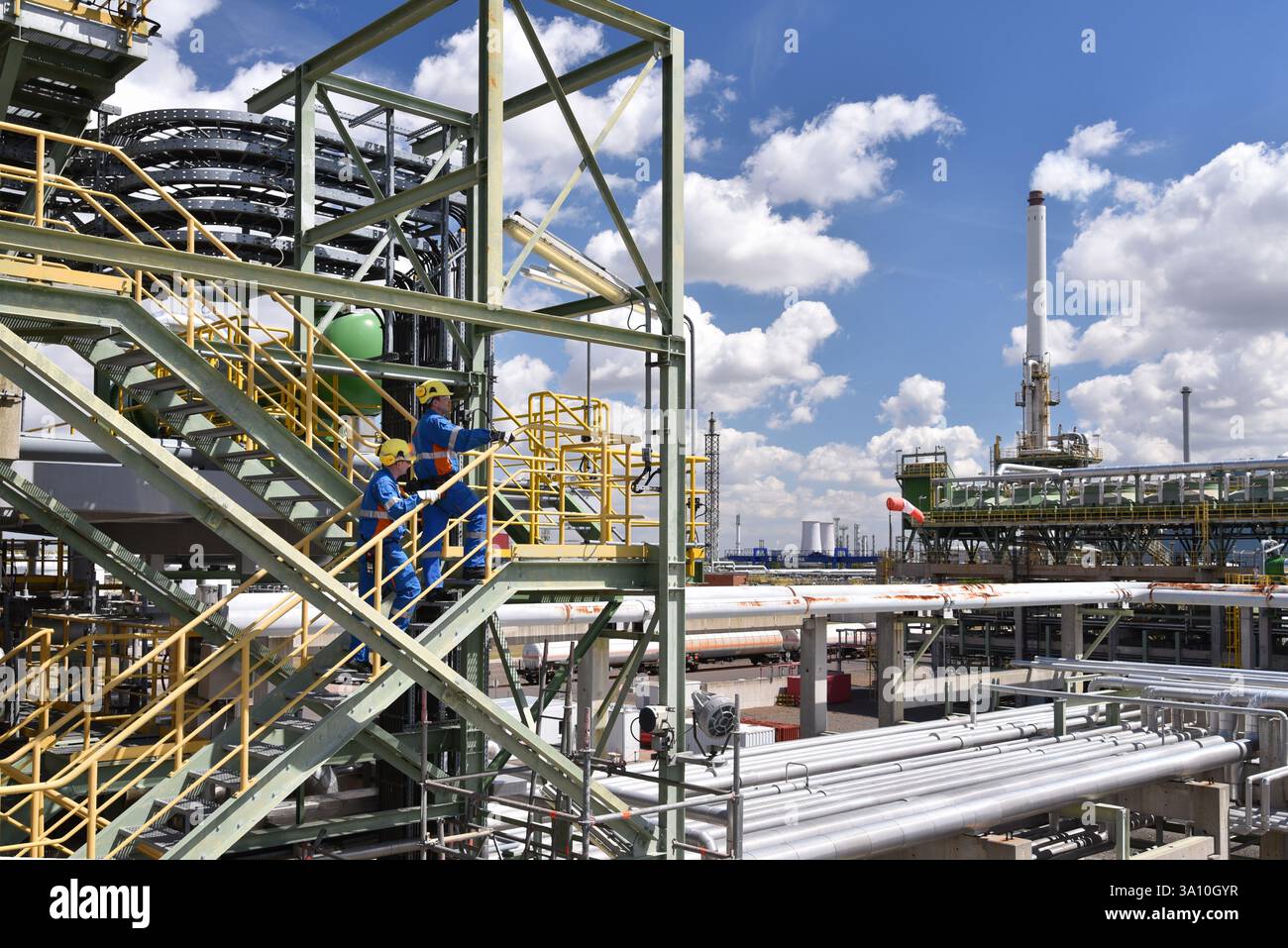 Workers in work clothes in a rafinery - modern equipment and buildings ...