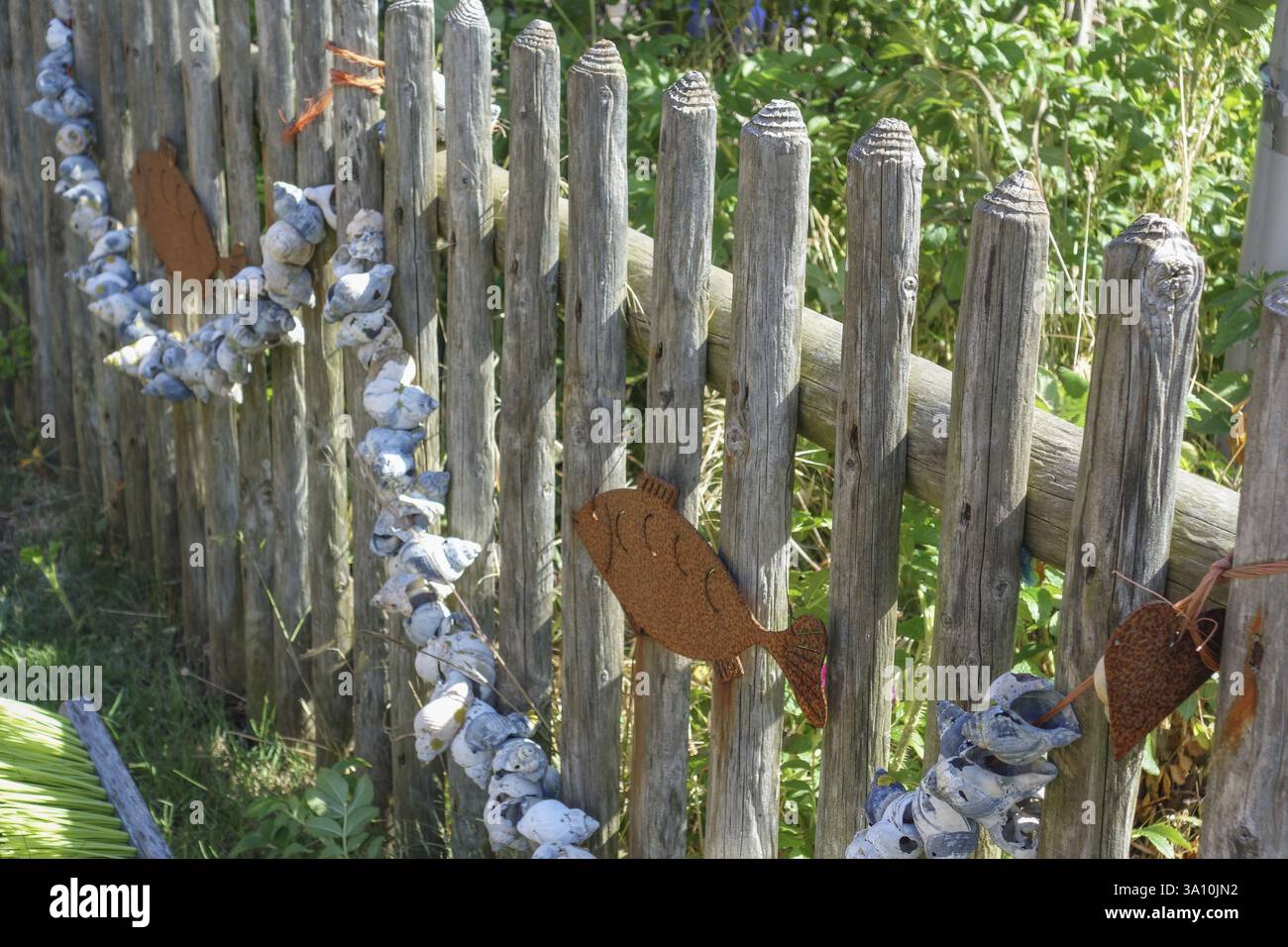Rustic fence with decorative shell and fish ornament chain, juist ...