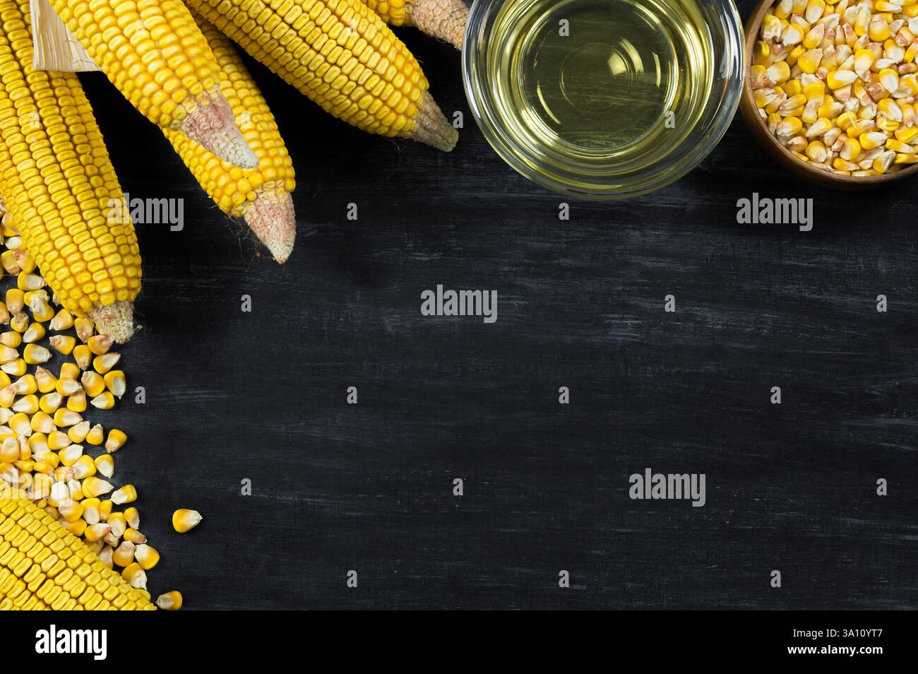 Pouring Corn oil in glass bottle with dried corn groats and kernels on ...