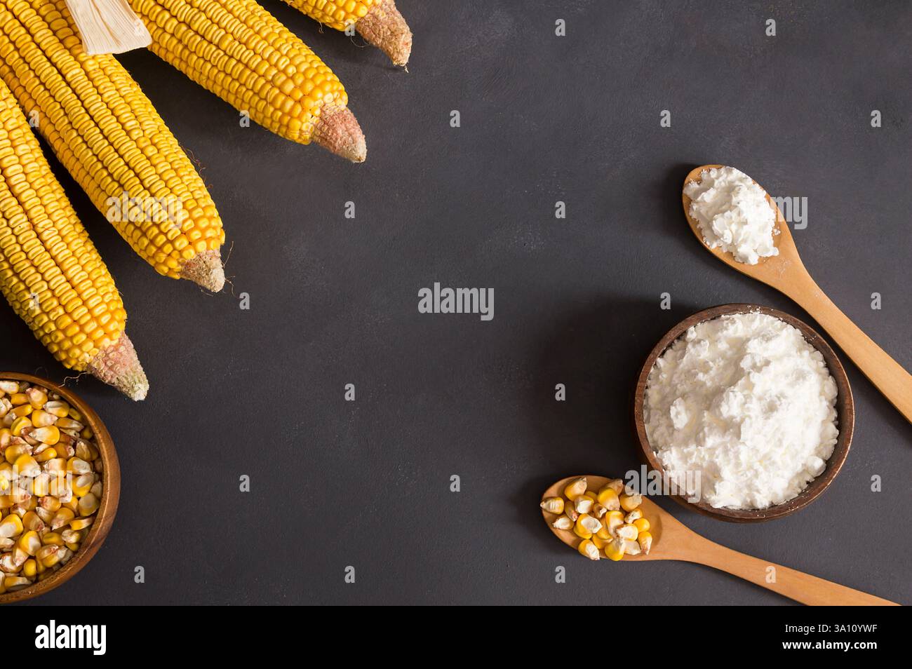Corn starch in wooden bowl and spoon with dried corn groats, kernels on ...