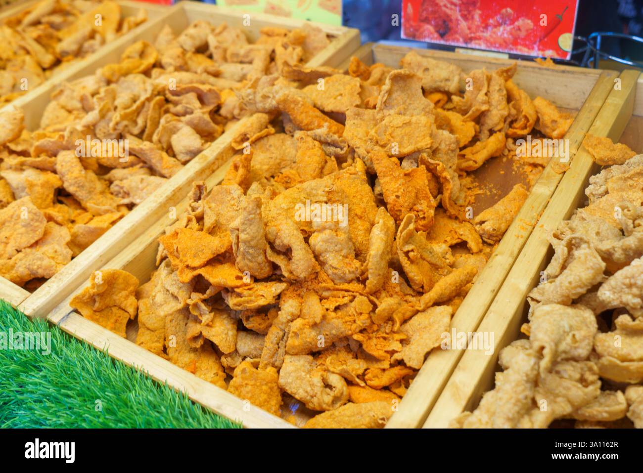 close-up shot of seasoned Chicken Skin cracklings on display in wooden ...