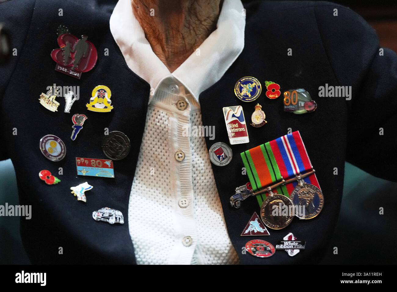 Medals and stickers are seen on the jacket of WWII Veteran Robbie Hall ...