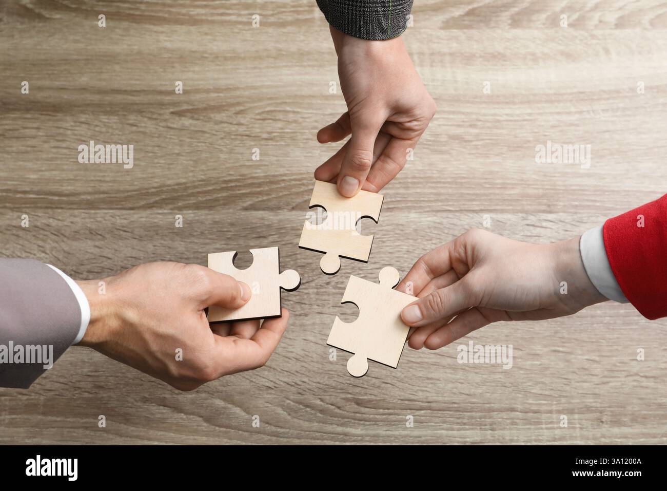 Teamwork. People putting puzzle pieces together at wooden table, top view Stock Photo - Alamy