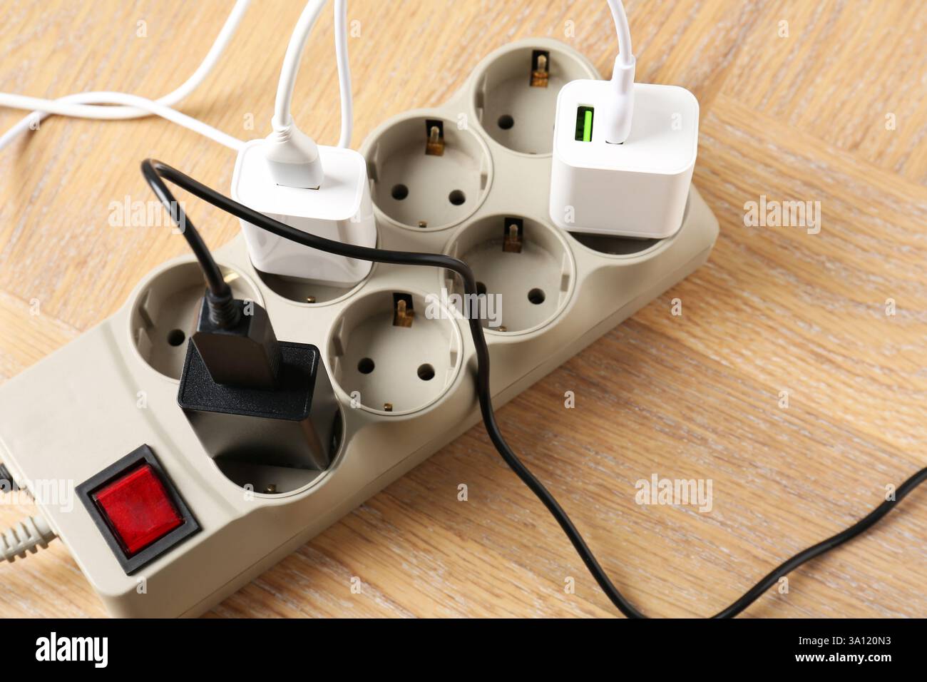 USB adapters with charge cables in power strip on wooden table, above ...