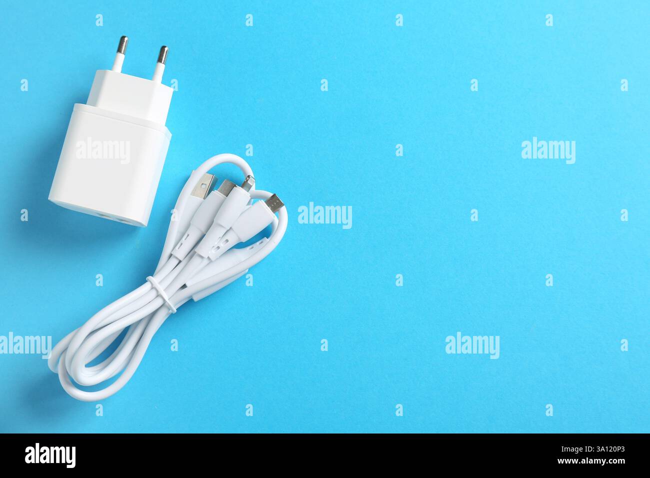 USB power adapter and triple charge cable on light blue background ...