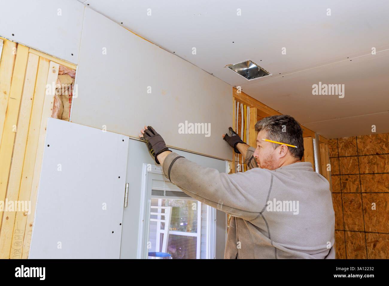 Carpenter is carefully placing drywall sheetrock sheets on interior ...