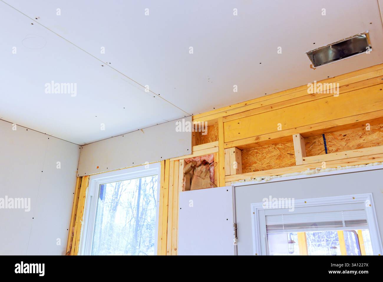 Drywall is being installed alongside wooden framing in a home ...