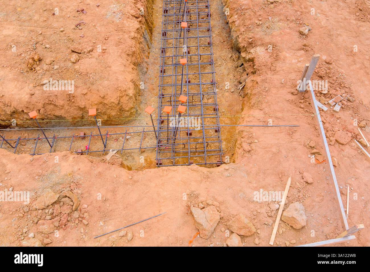 Workers prepare trench with steel reinforcement for concrete foundation ...