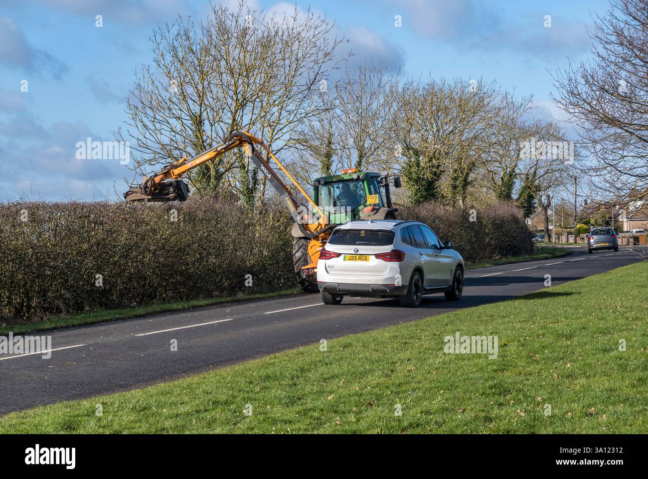 Trimming hedge tops with motorised trimmer on back of John Deere ...
