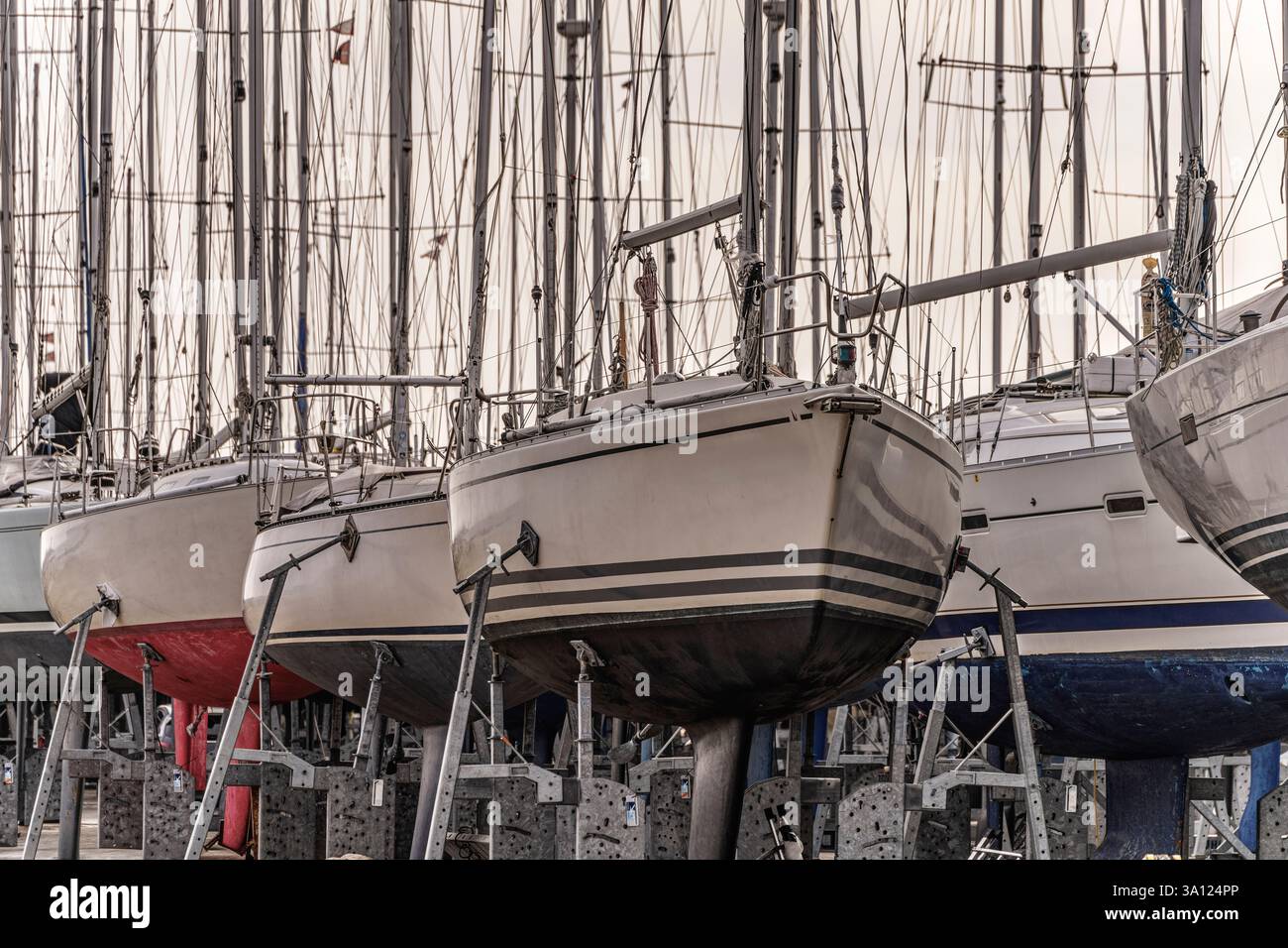 Several sailboats are docked in a thorough harbor storage area, each ...