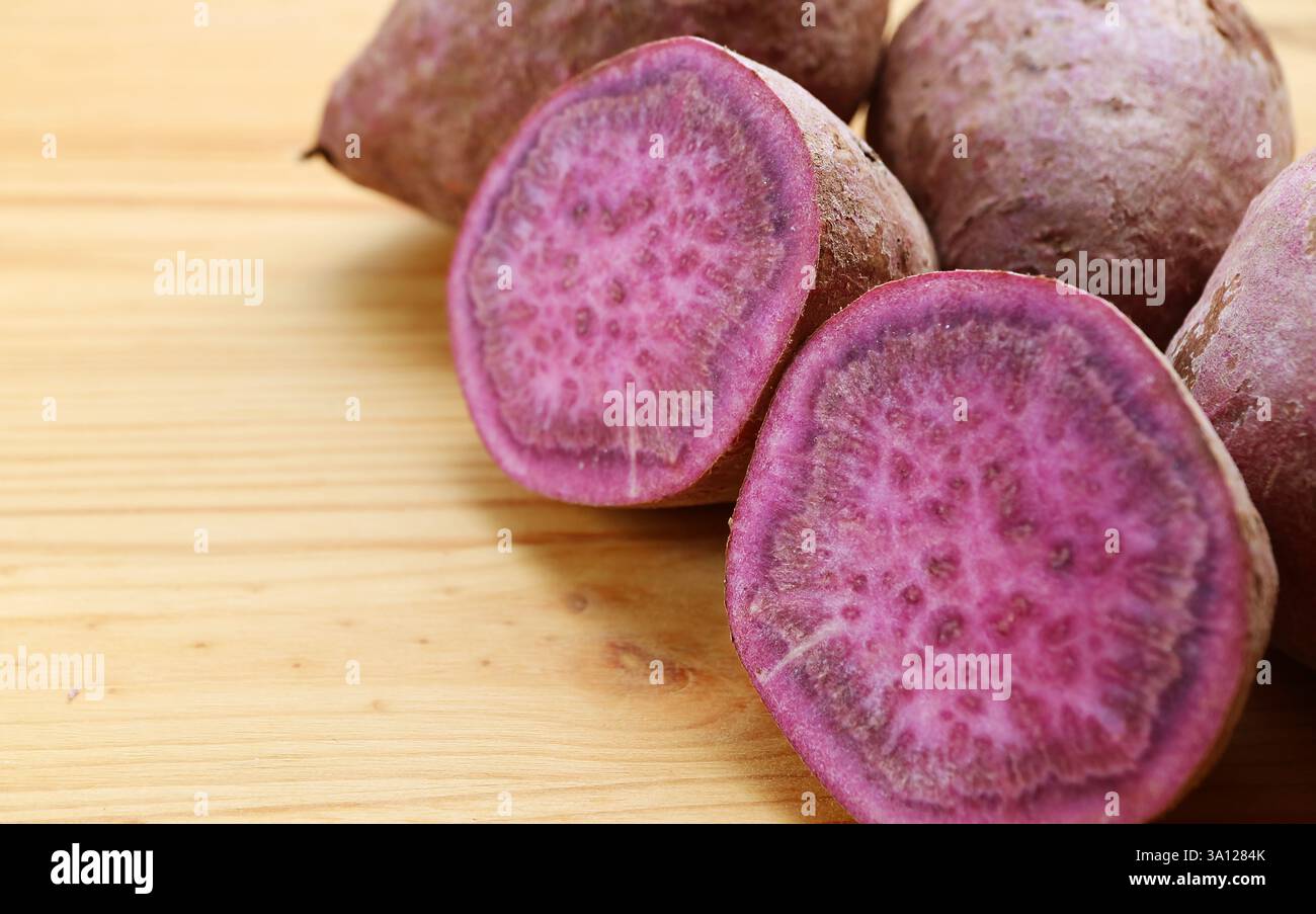 Closeup of Cross-section of Raw Purple Sweet Potatoes with Blurry Whole ...