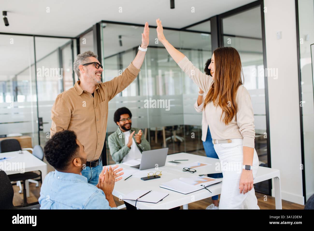 Energetic business professionals celebrate progress with a high-five ...