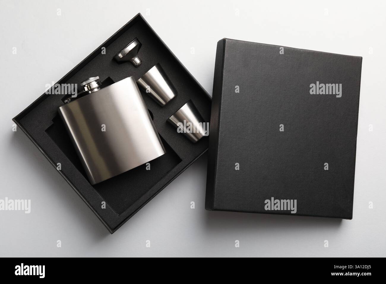 Hip flask, cups and funnel in package on white background, top view ...