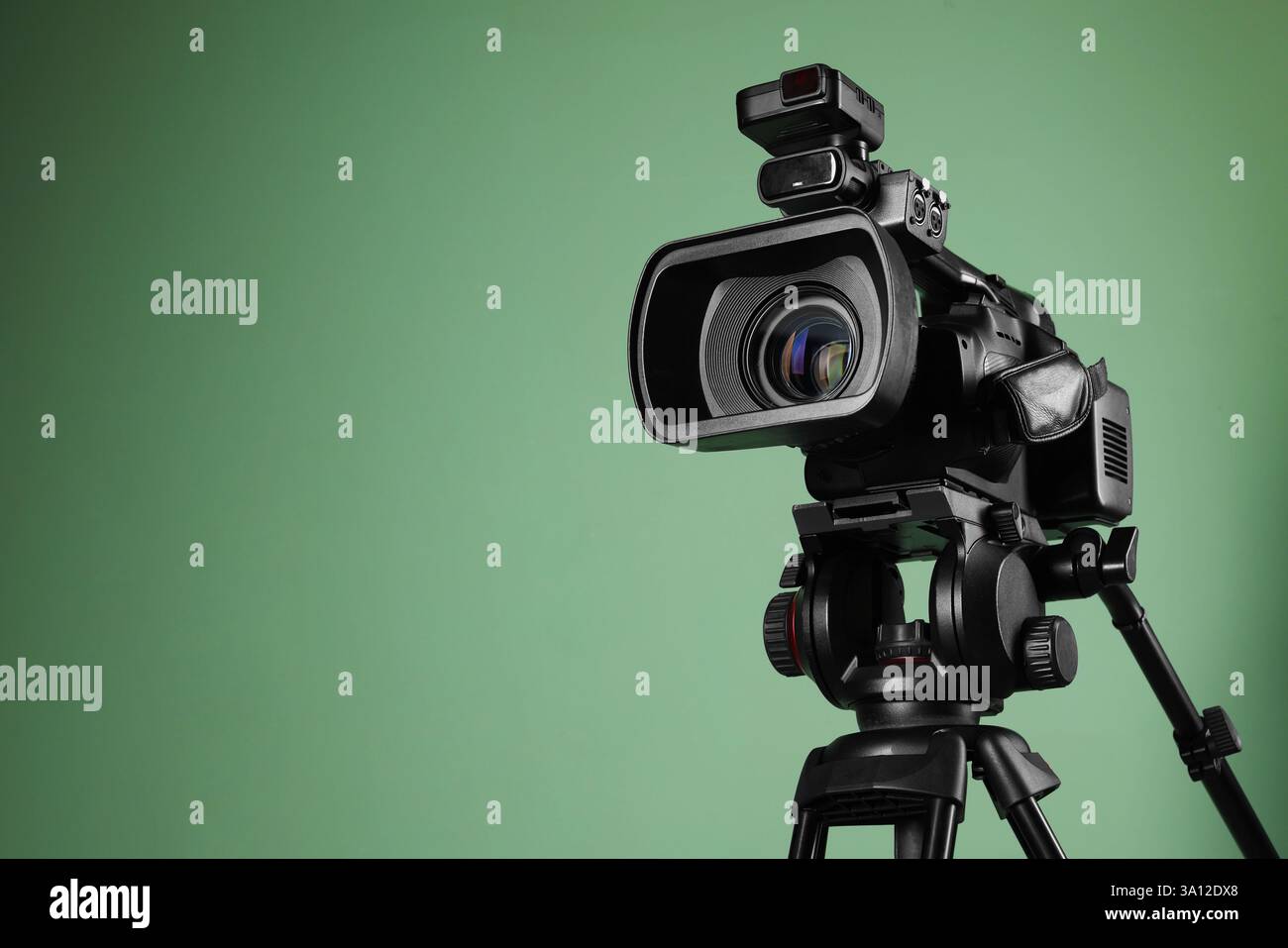 Modern professional video camera on greyish green background, space for ...