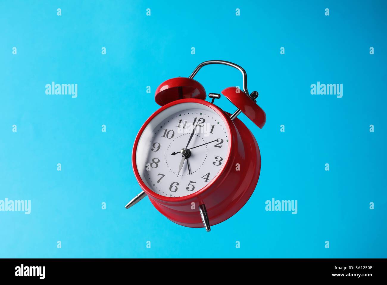 Red alarm clock in air on light blue background Stock Photo - Alamy