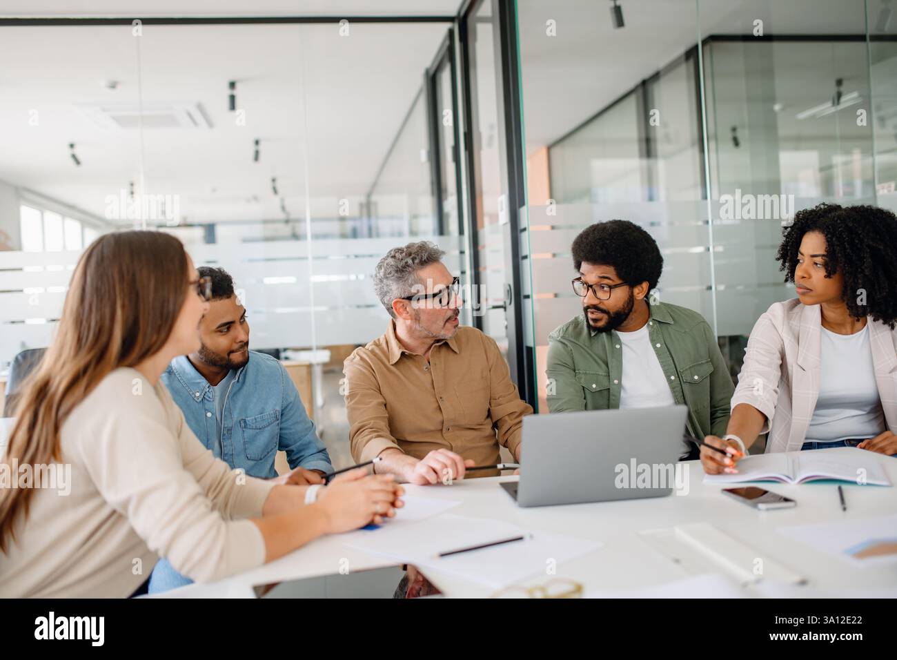 A business team engaging in an insightful strategy meeting in a contemporary office setting ...