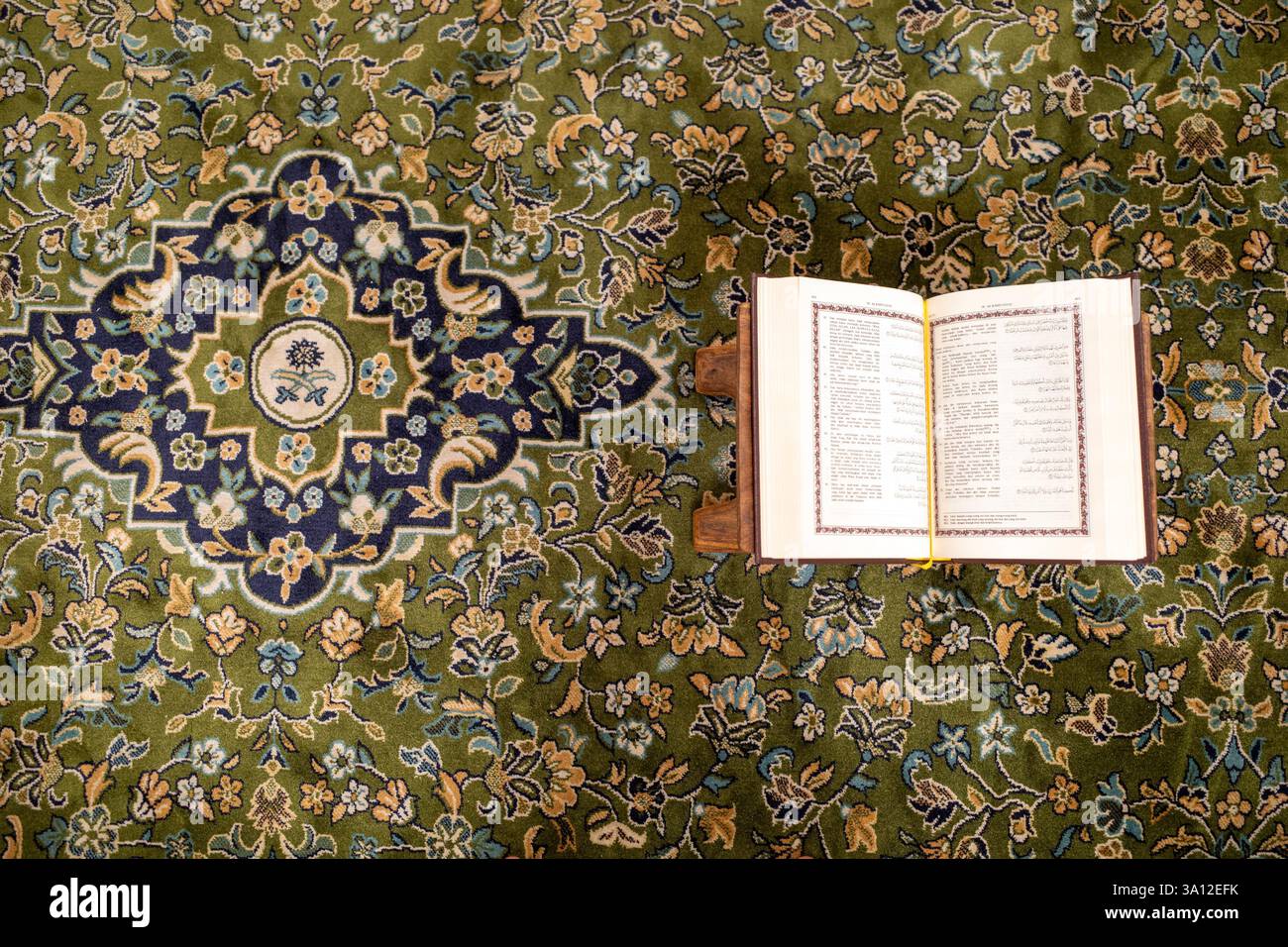 An opened holy book of the Quran on a green carpet at the Prophet ...