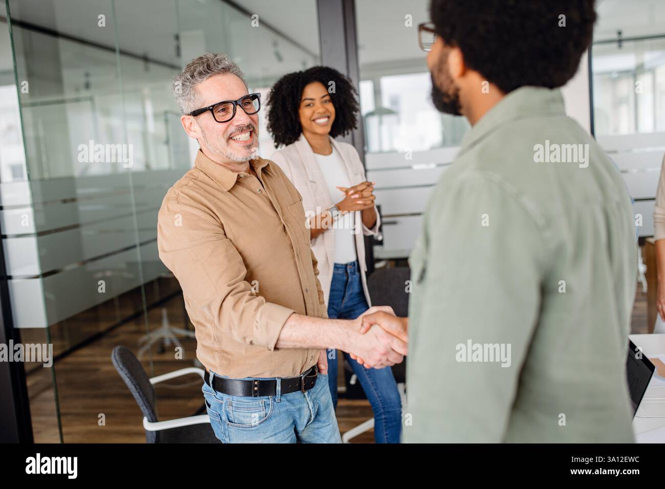 A professional handshake between two business colleagues in a modern office. Smiling coworkers ...