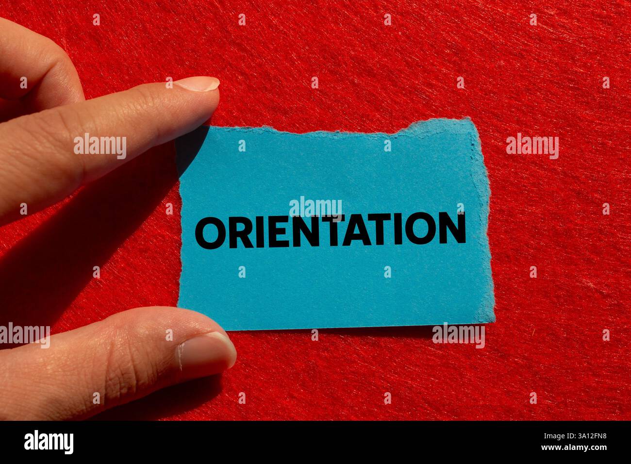 Orientation message written on ripped torn blue paper on red background ...