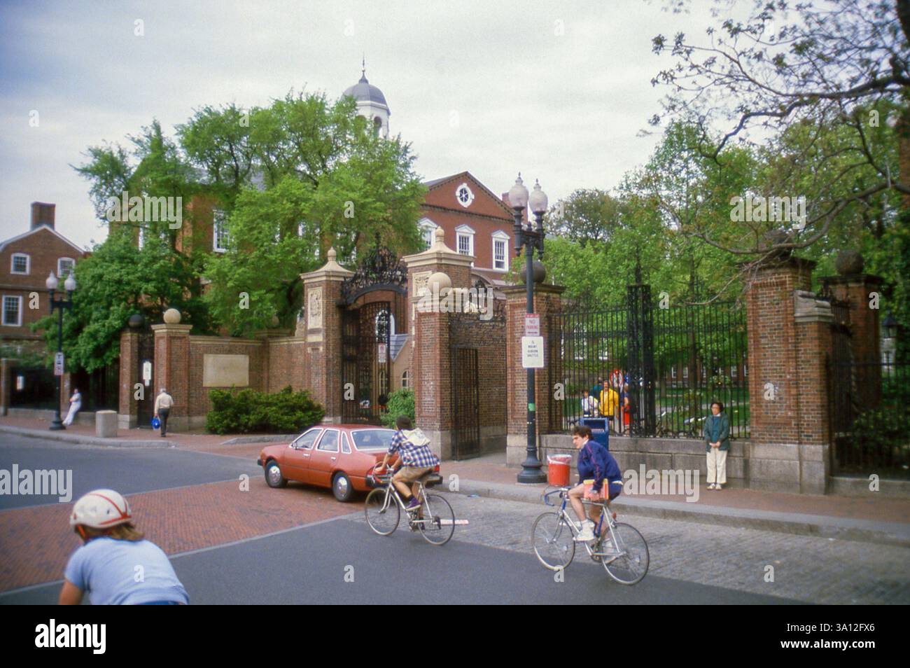 Bikers in Harvard. Harvard College building and Johnston Gate in ...