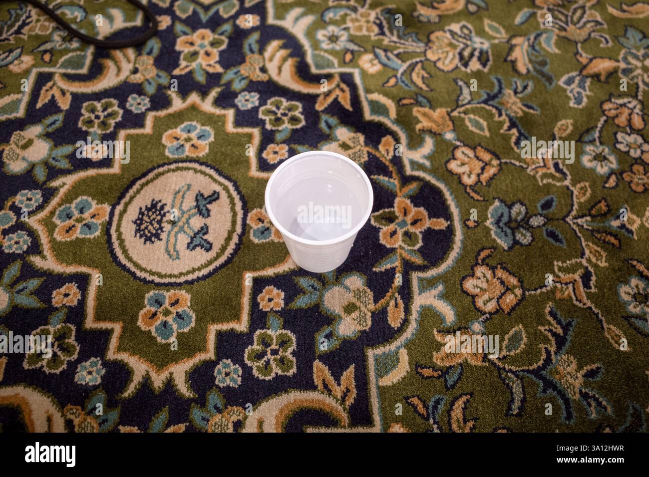 Zam zam water on a white plastic cup on a green carpet at the Prophet ...