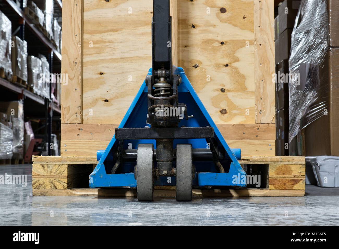 Blue pallet jack under wooden crate pallet ground level industrial ...