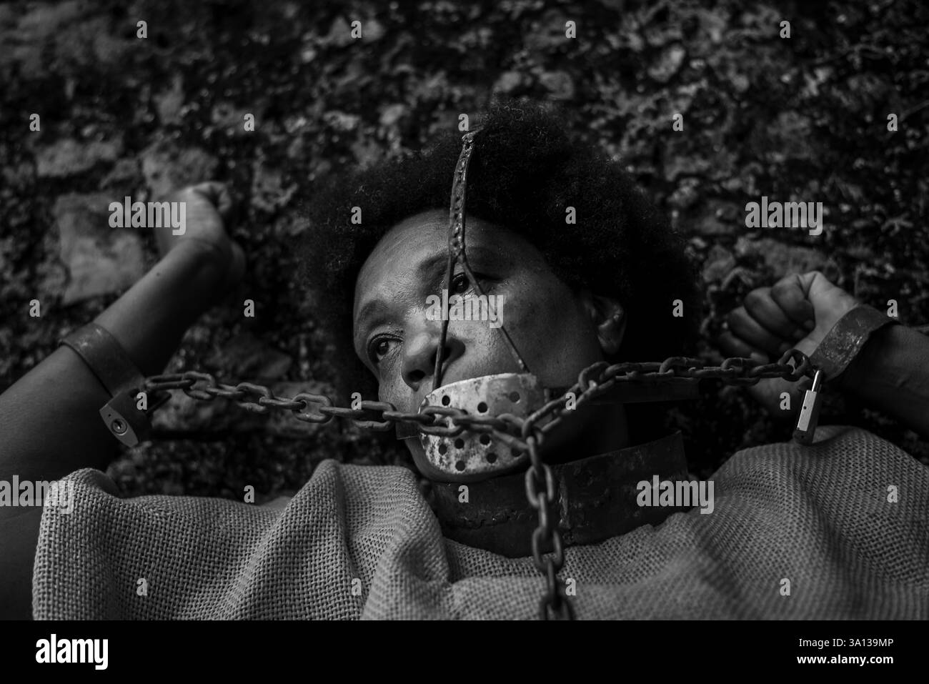 Portrait of a black woman's face with an iron mask stuck in her mouth ...