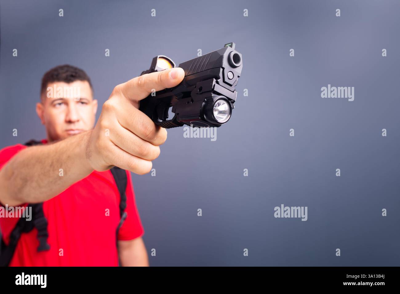 Studio portrait of a shooting instructor pointing a firearm to the side ...