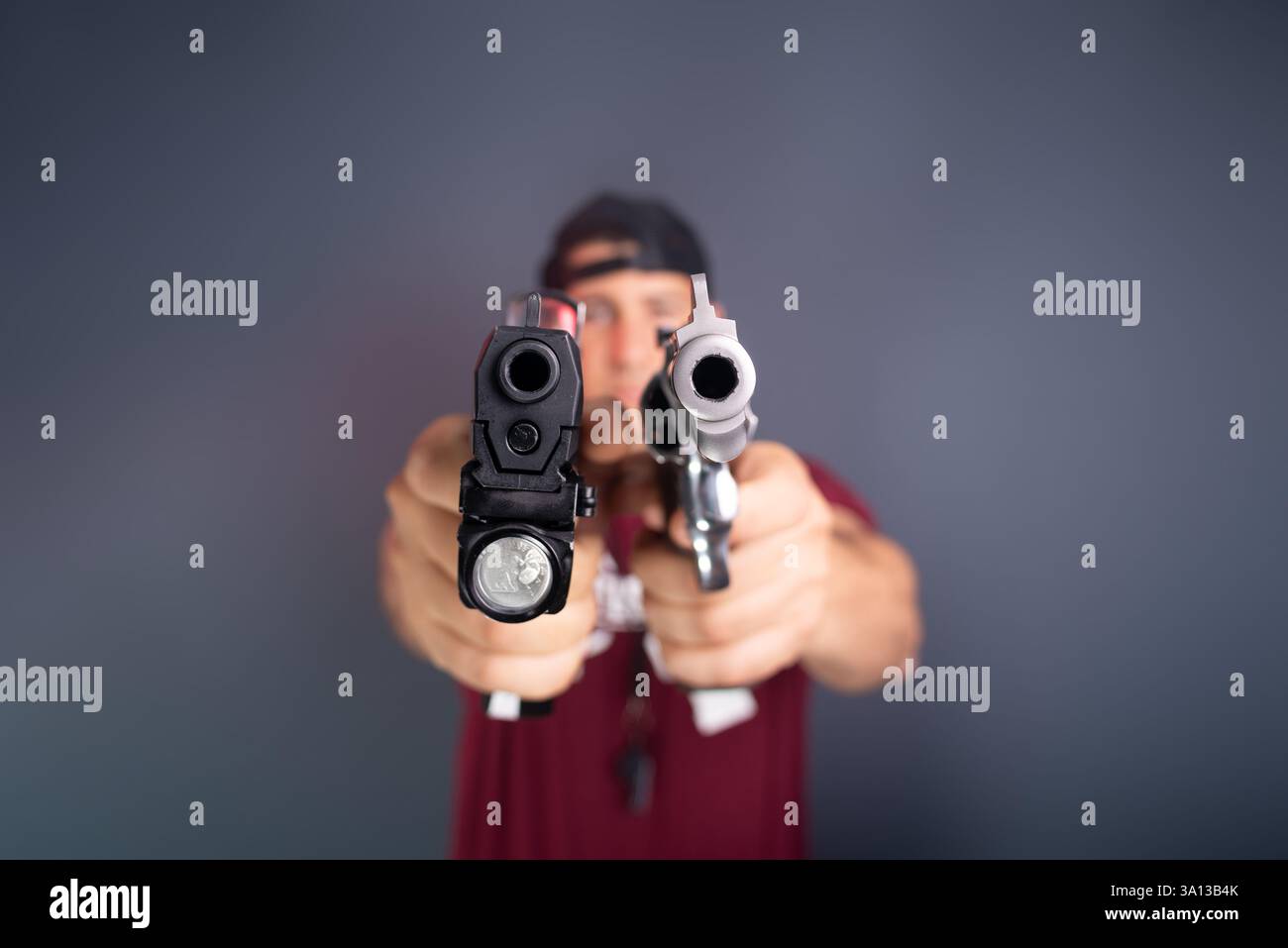 Studio portrait of a shooting instructor wearing a hat pointing two ...