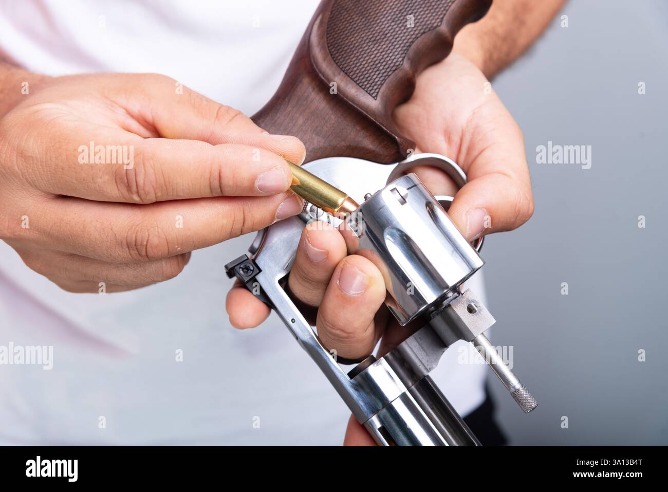 Detail of a shooting instructor loading a bullet into a silver revolver ...