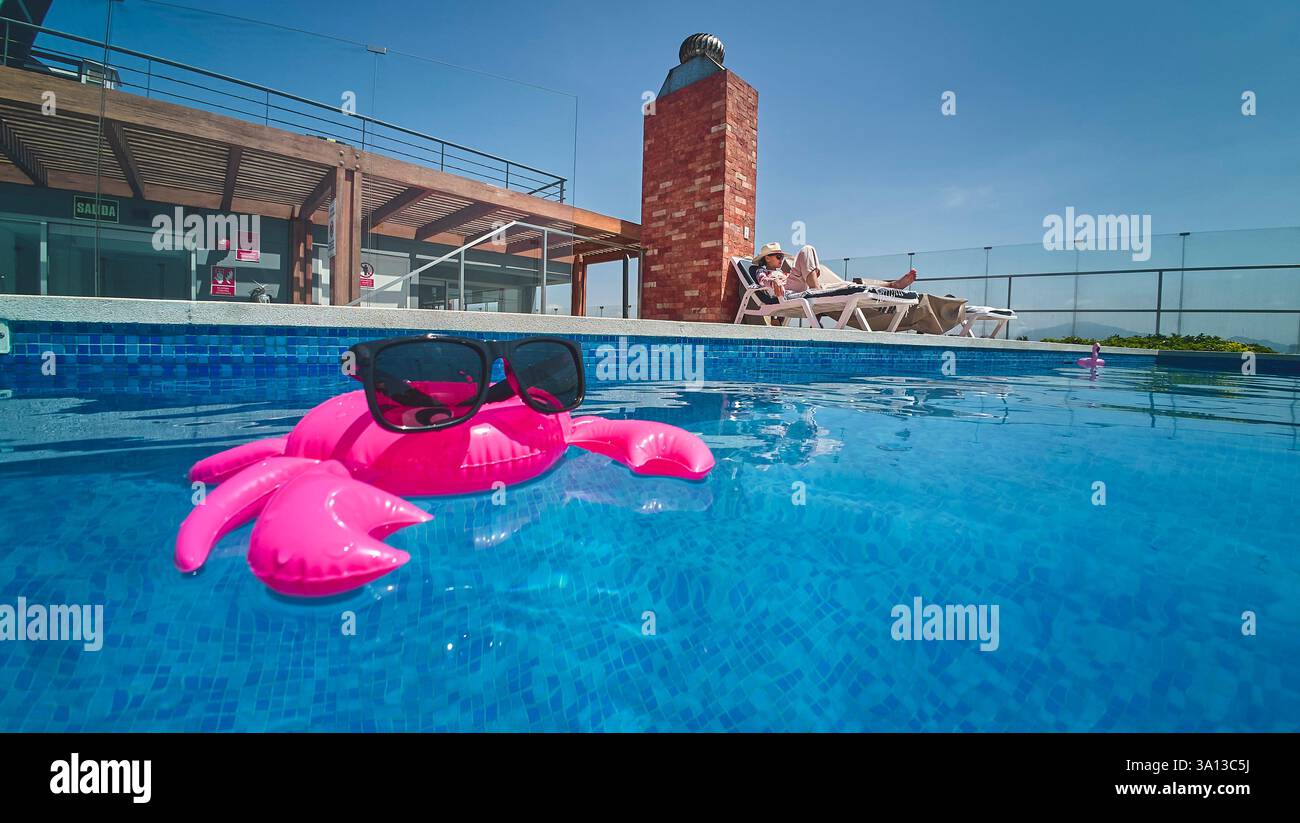 Inflatable pink crab wearing sunglasses floating in swimming pool ...