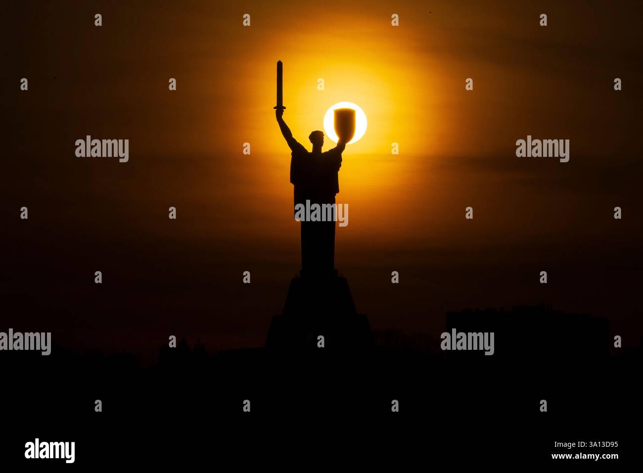 Sun setting behind the Mother Ukraine statue in Kyiv. The sculpture is ...