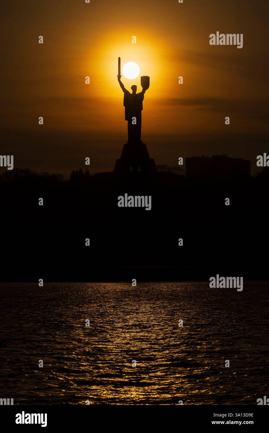 Sun setting behind the Mother Ukraine statue in Kyiv. The sculpture is ...