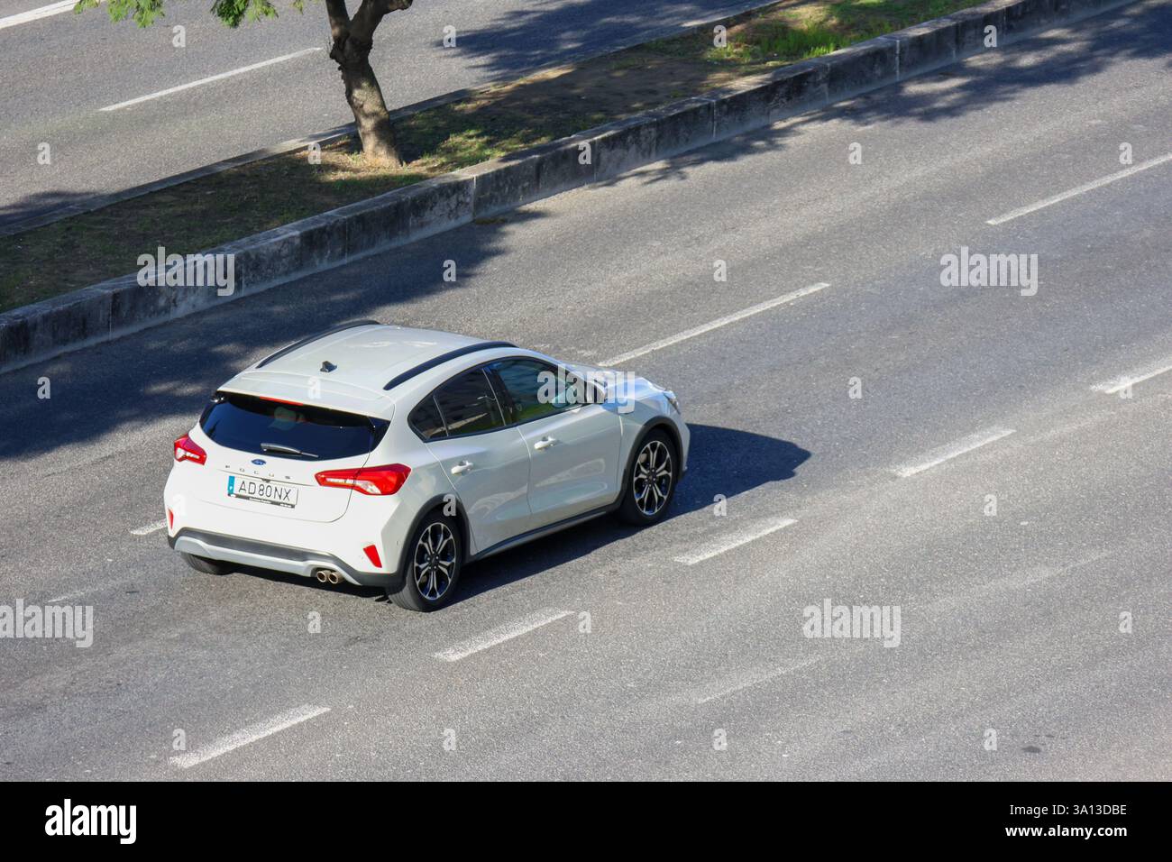 Ford focus car driving on asphalt road next to concrete curb and tree ...