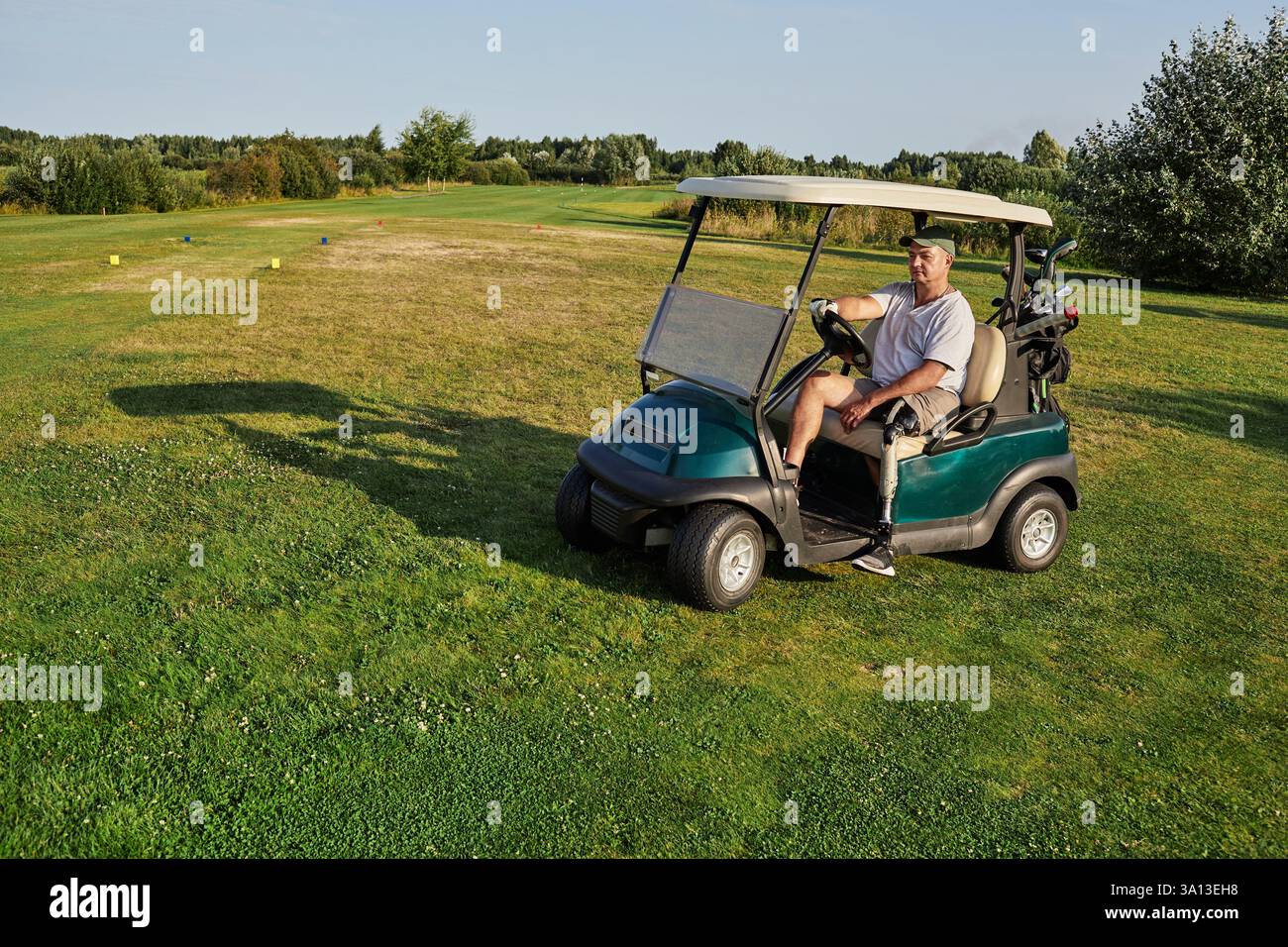 A golfer with a prosthetic leg sits in a golf cart, ready to tee off ...