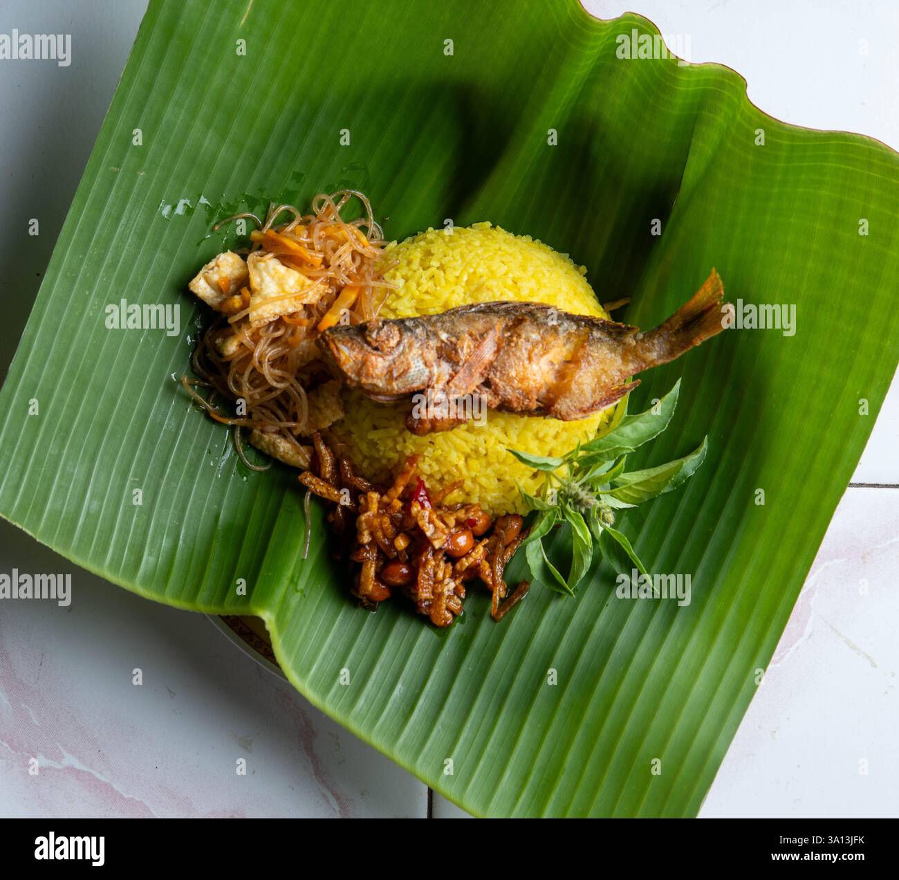 Authentic Indonesian Nasi Kuning served on banana leaves with fried ...